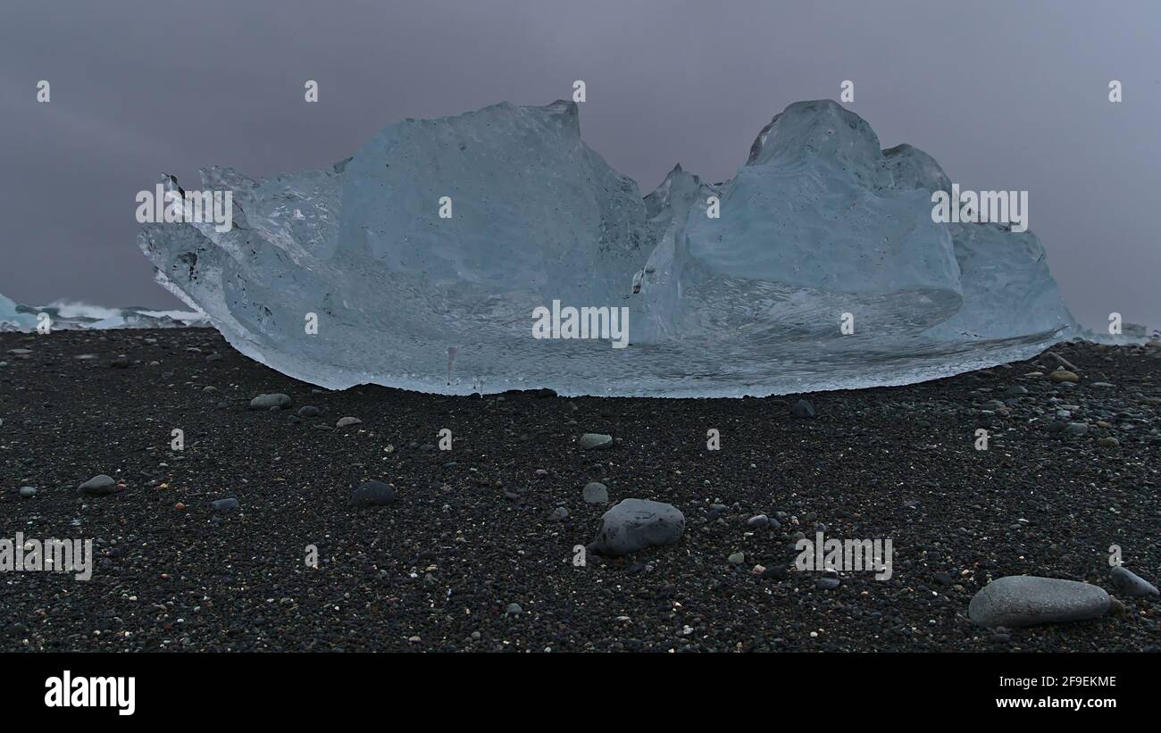Bizarre looking small iceberg with clear surface on the shore of famous ...