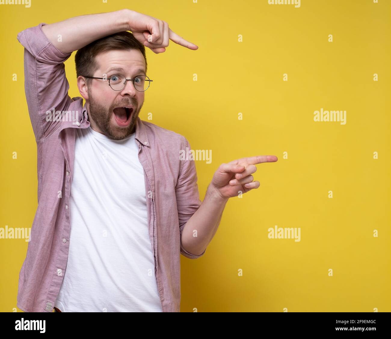 Funny man points index fingers at something, he stands in an unusual ...
