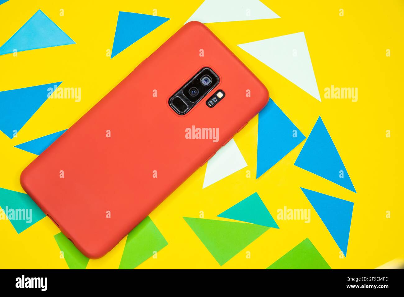 A top view of a red mobile phone on a yellow surface surrounded by ...