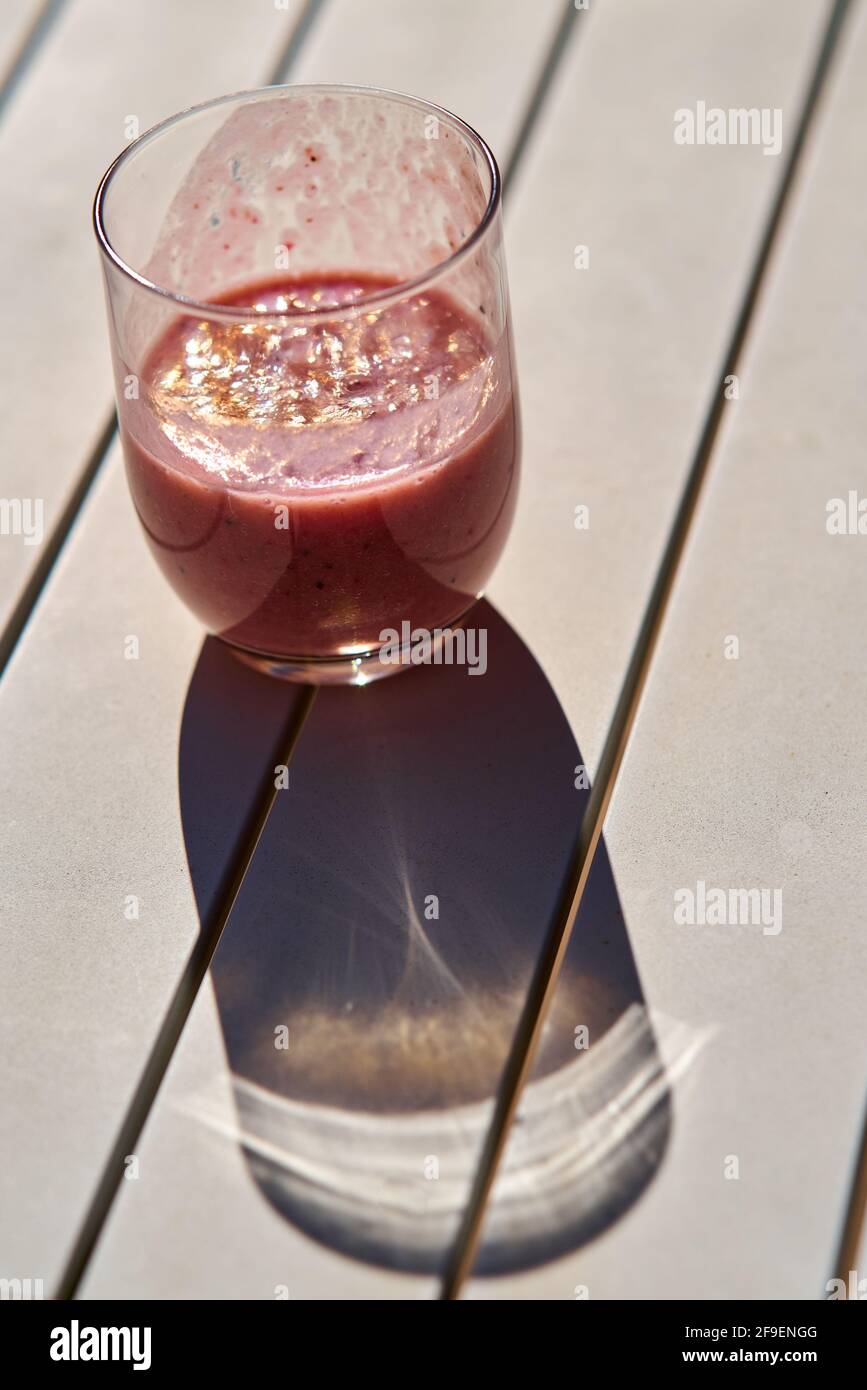 Fruit smoothie with red color on white table under sunlight Stock Photo ...