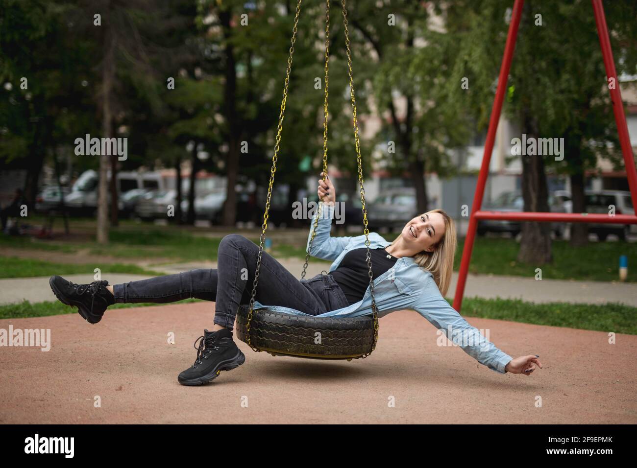 A blonde cute elegant attractive woman having fun on the swing in the ...