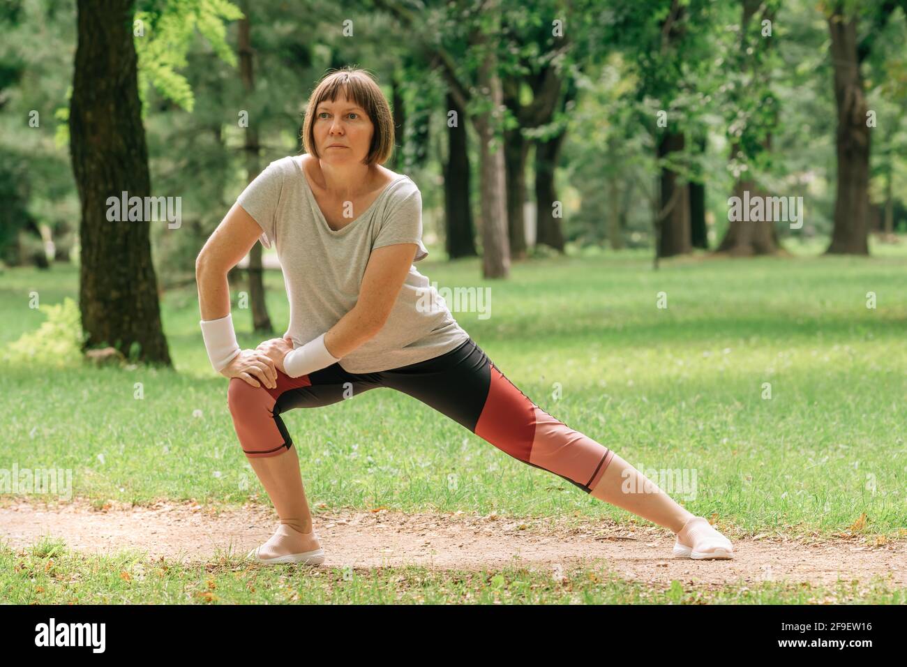 Female jogger stretching muscles and warming up for running exercise in ...