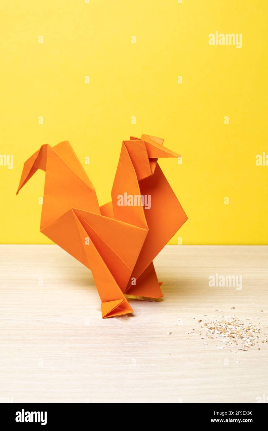 A vertical shot of an orange origami chicken on a wooden surface Stock ...