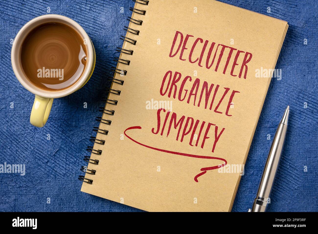Declutter, organize, simplify. Motivational handwriting in a spiral notebook with a cup of ...