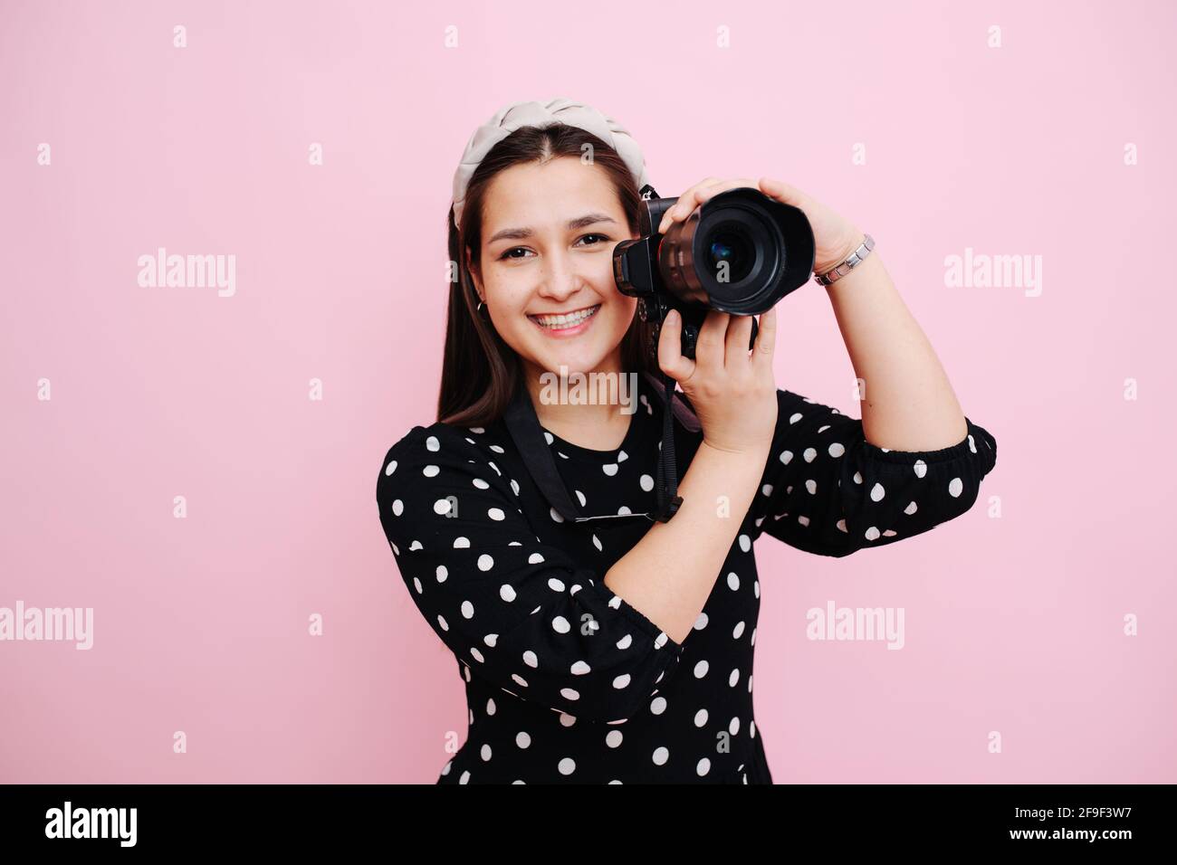 Smiling woman in modest clothes posing with her digital camera over ...