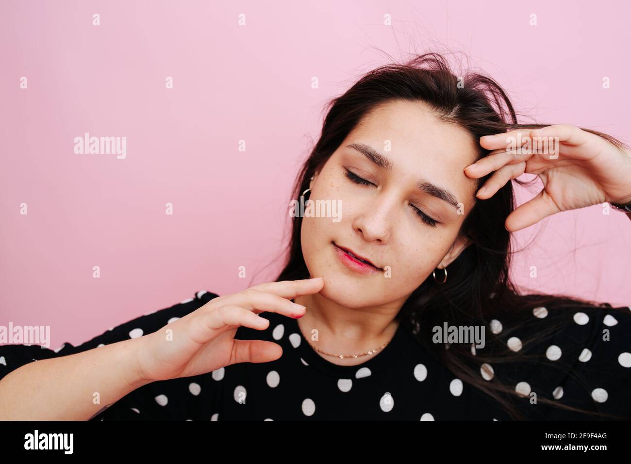 Relaxed, dozed out young woman. Her eyes closed, she's touching her ...