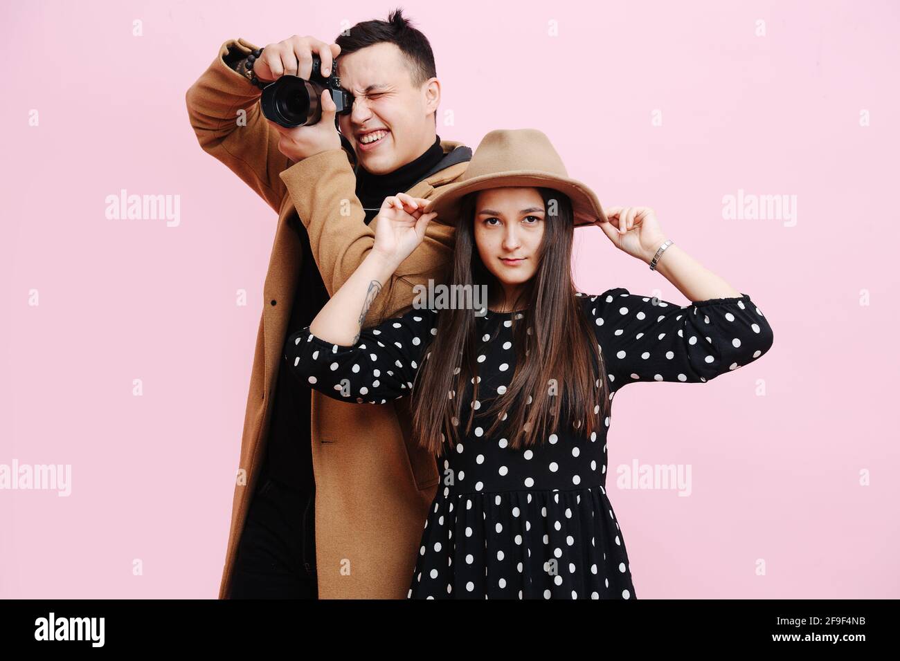 Cute young couple standing close, man taking image on a digital camera ...