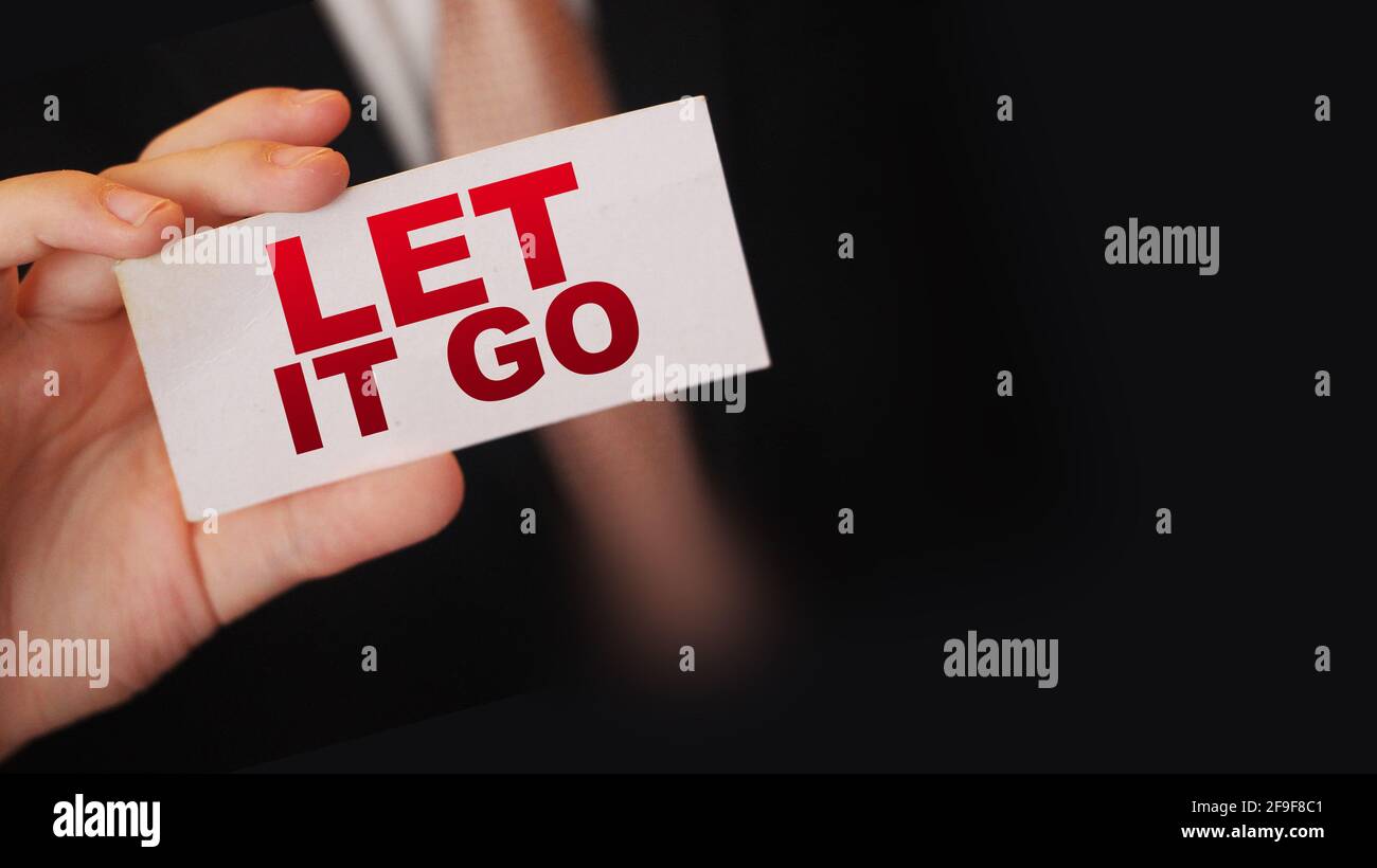 Closeup on businessman holding a card with text LET IT GO, business ...