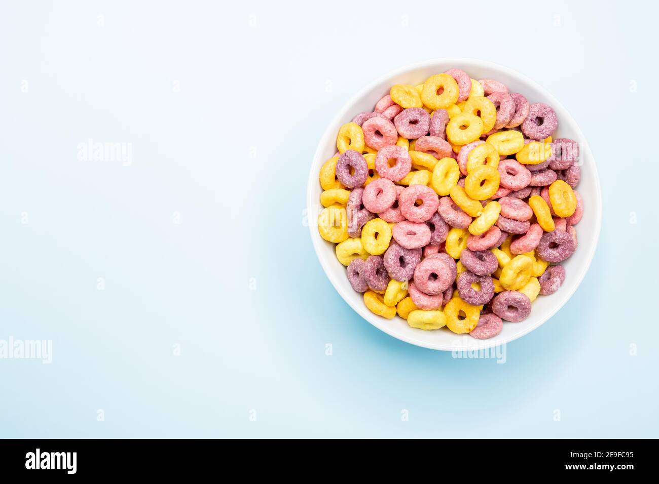 A top view of colorful cereal rings on a bowl isolated on light blue ...