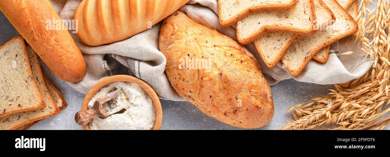Various crispy breads and buns, wheat flour and ears on light gray ...