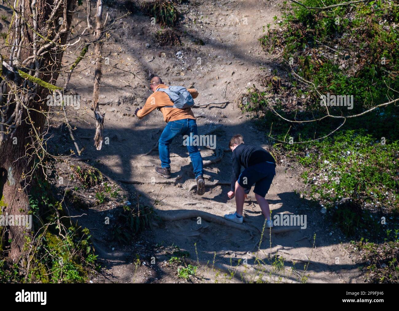 Middle aged man and young boy climbing together up a hilly path through ...