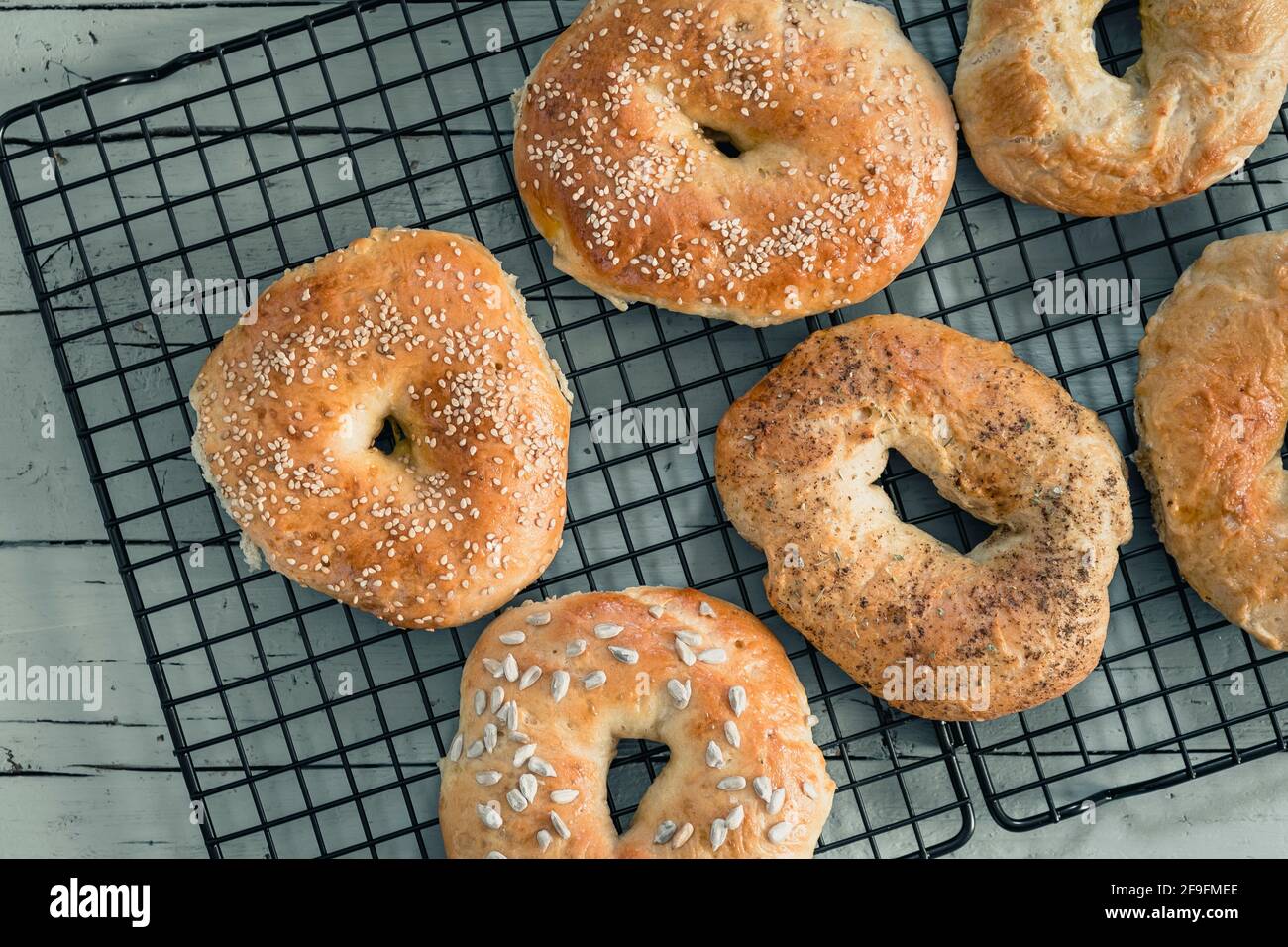 Homemade bagels lying on a cooling rack on a wooden table, top view ...