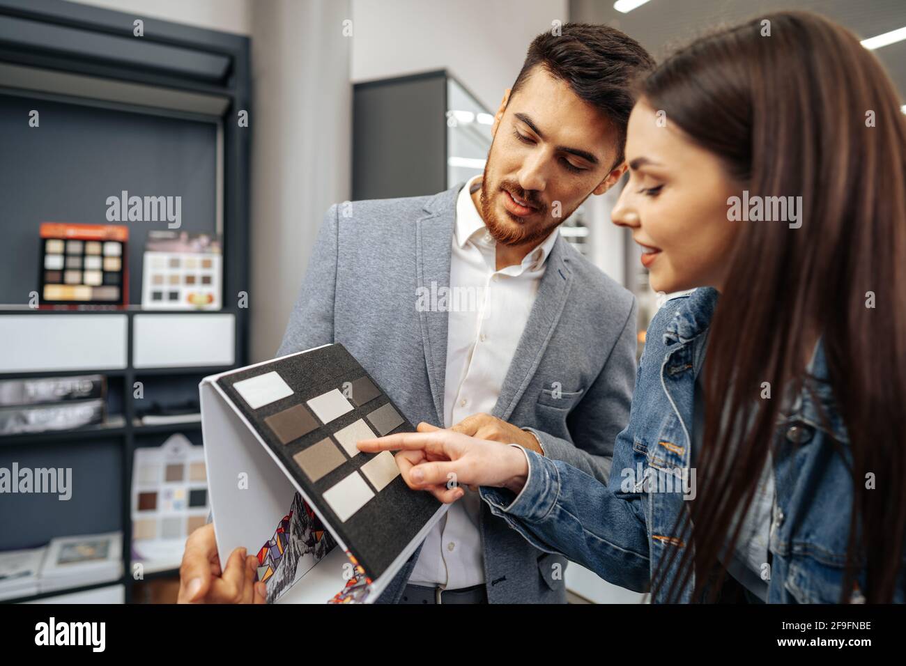 Salesman shows color swatches to lady customer for new kitchen ...