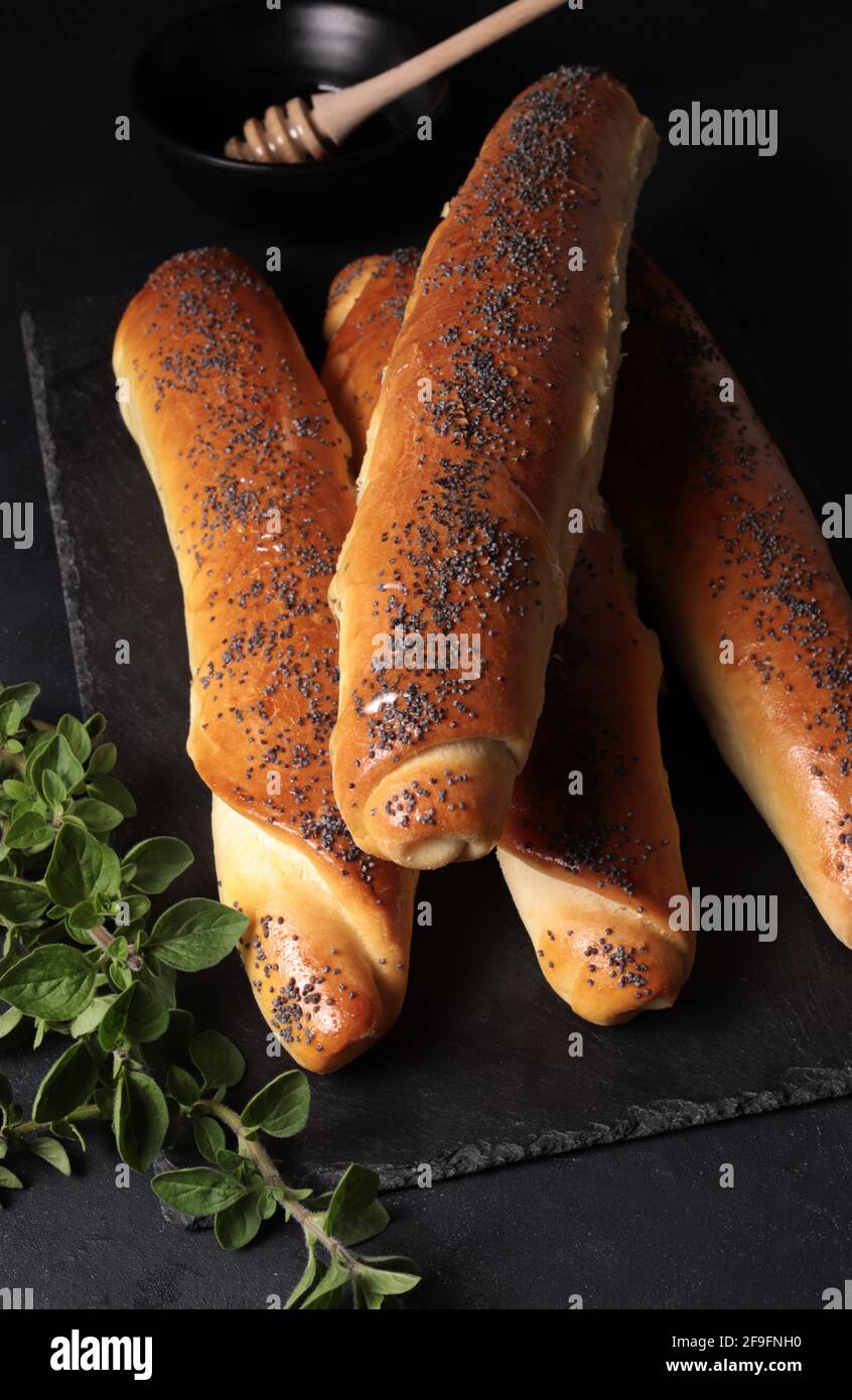 Homemade sticks with poppy seeds and honey in a bowl on dark background ...