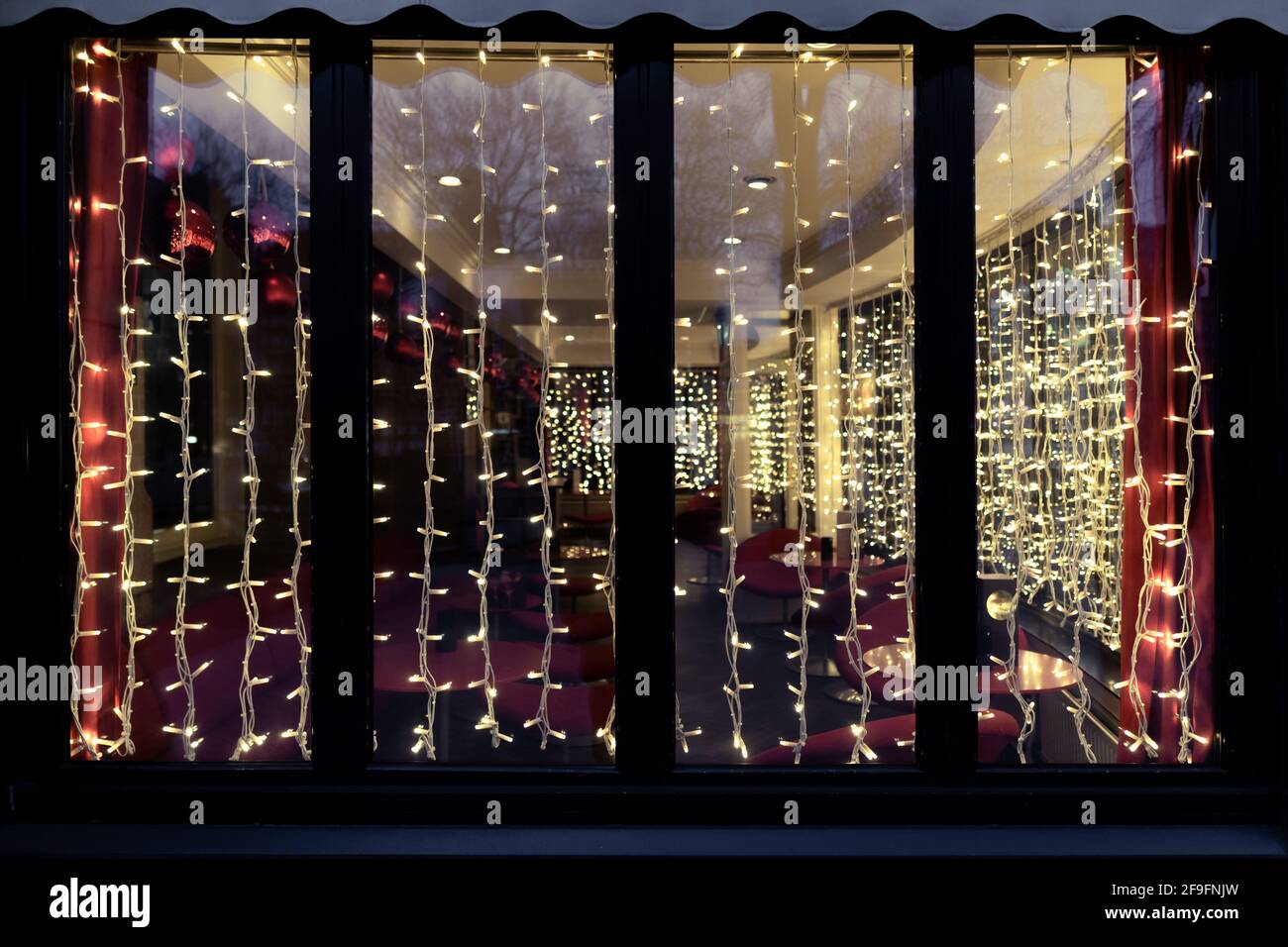 The interior of a cafe through windows decorated with light garlands at ...