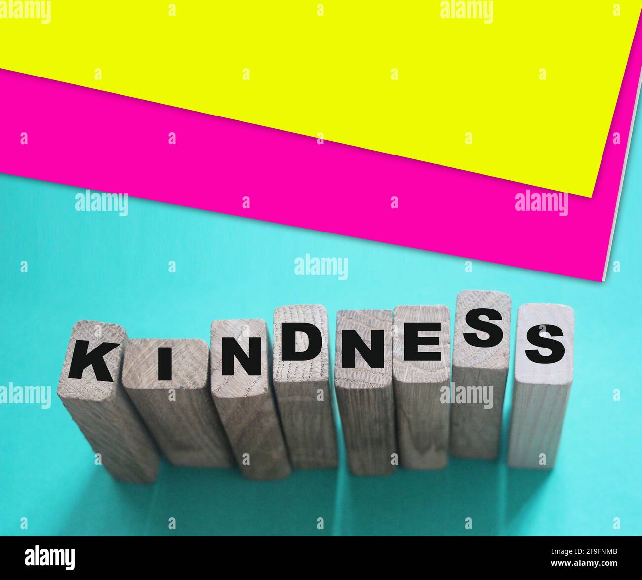 KINDNESS word made with wooden building blocks on neon aquamarine ...