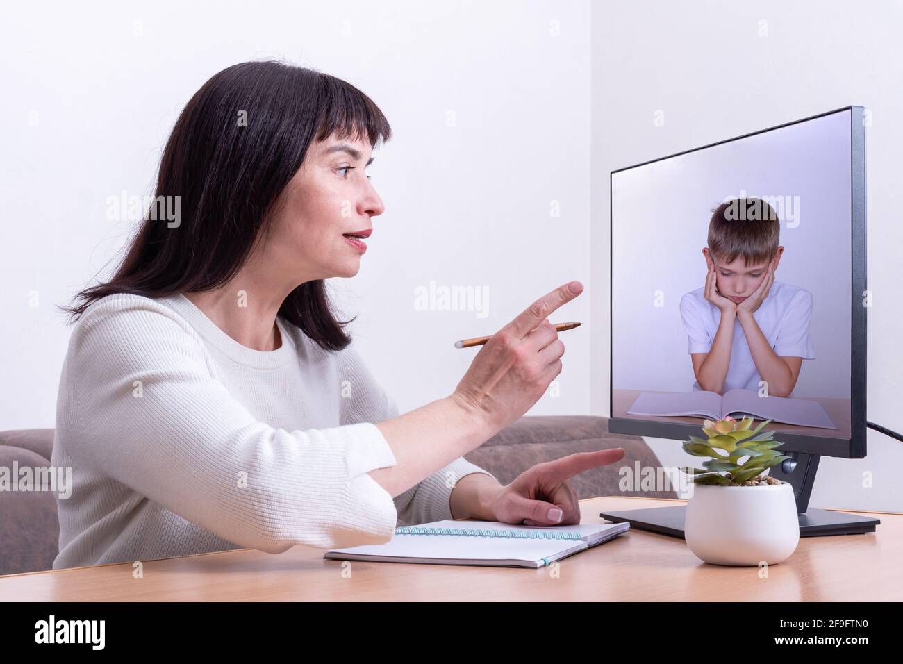 An attractive woman teacher sitting in front of a computer monitor ...