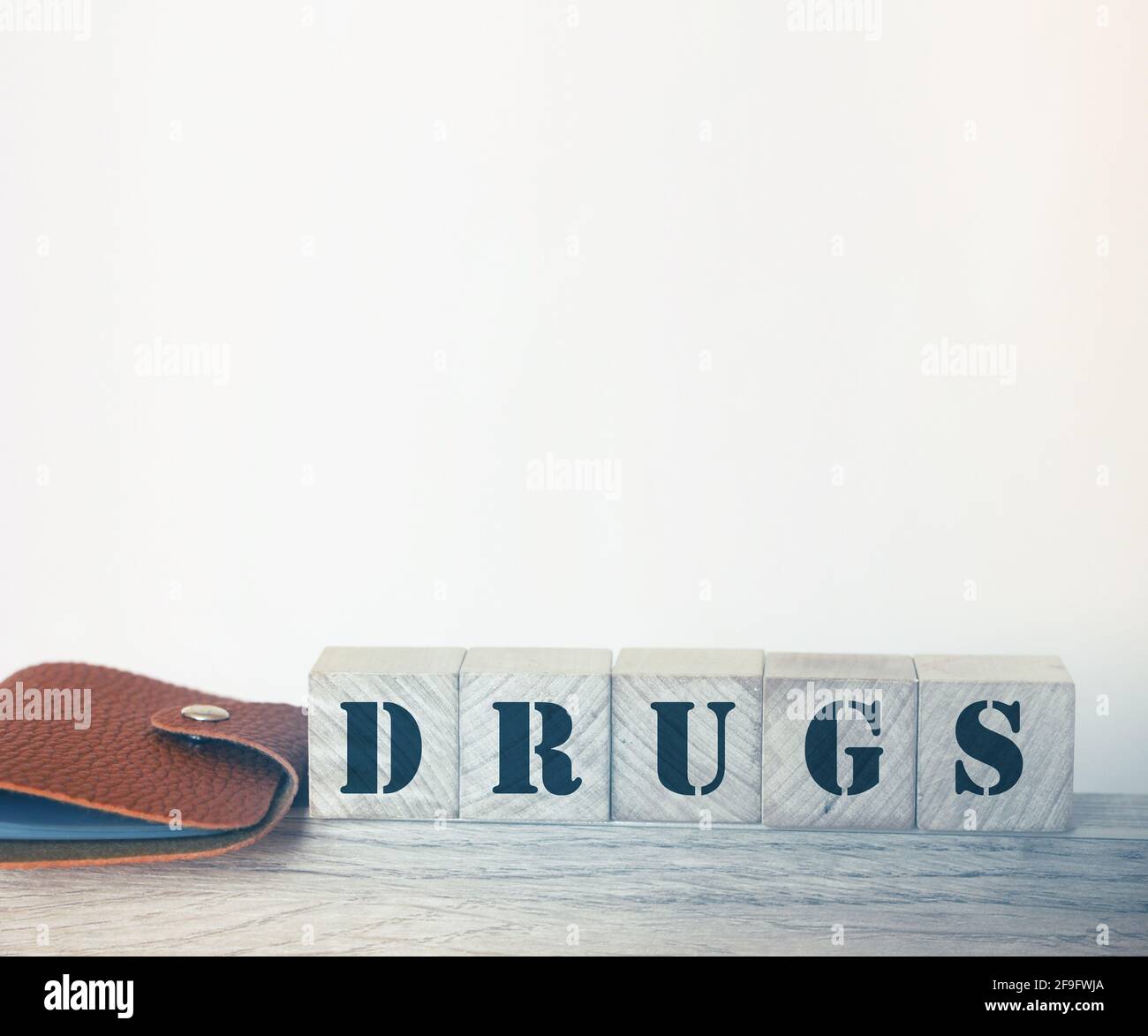 Drugs word on Wooden cubes on a wooden table. Keather wallet. Wasting ...