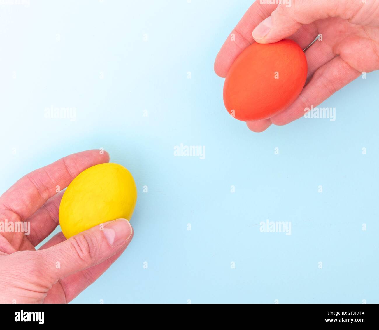 Happy Easter concept. Two hands give each other painted Easter eggs on ...