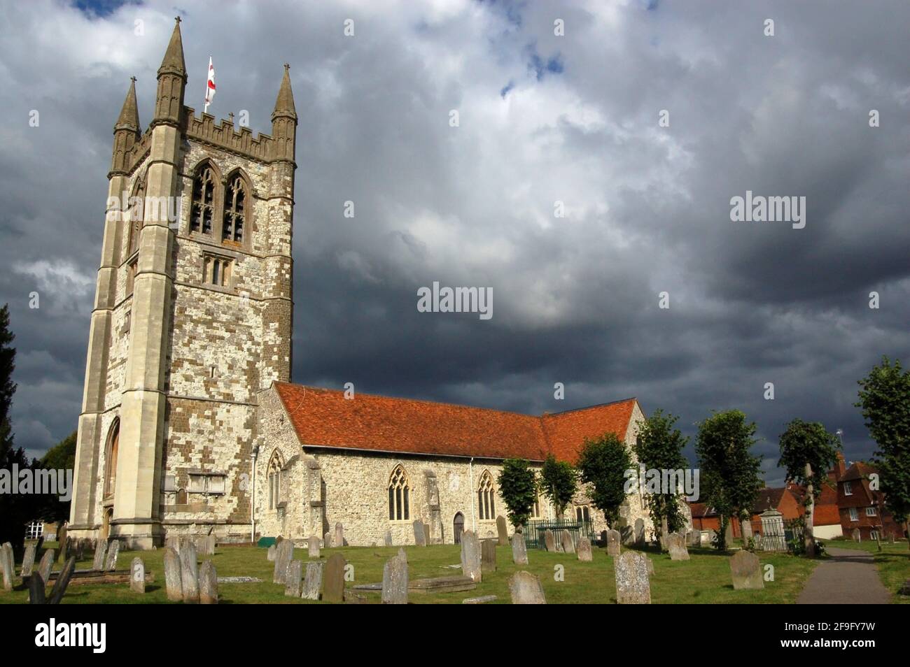 The parish church of Saint Andrew in Farnham, Surrey with a stormy sky ...