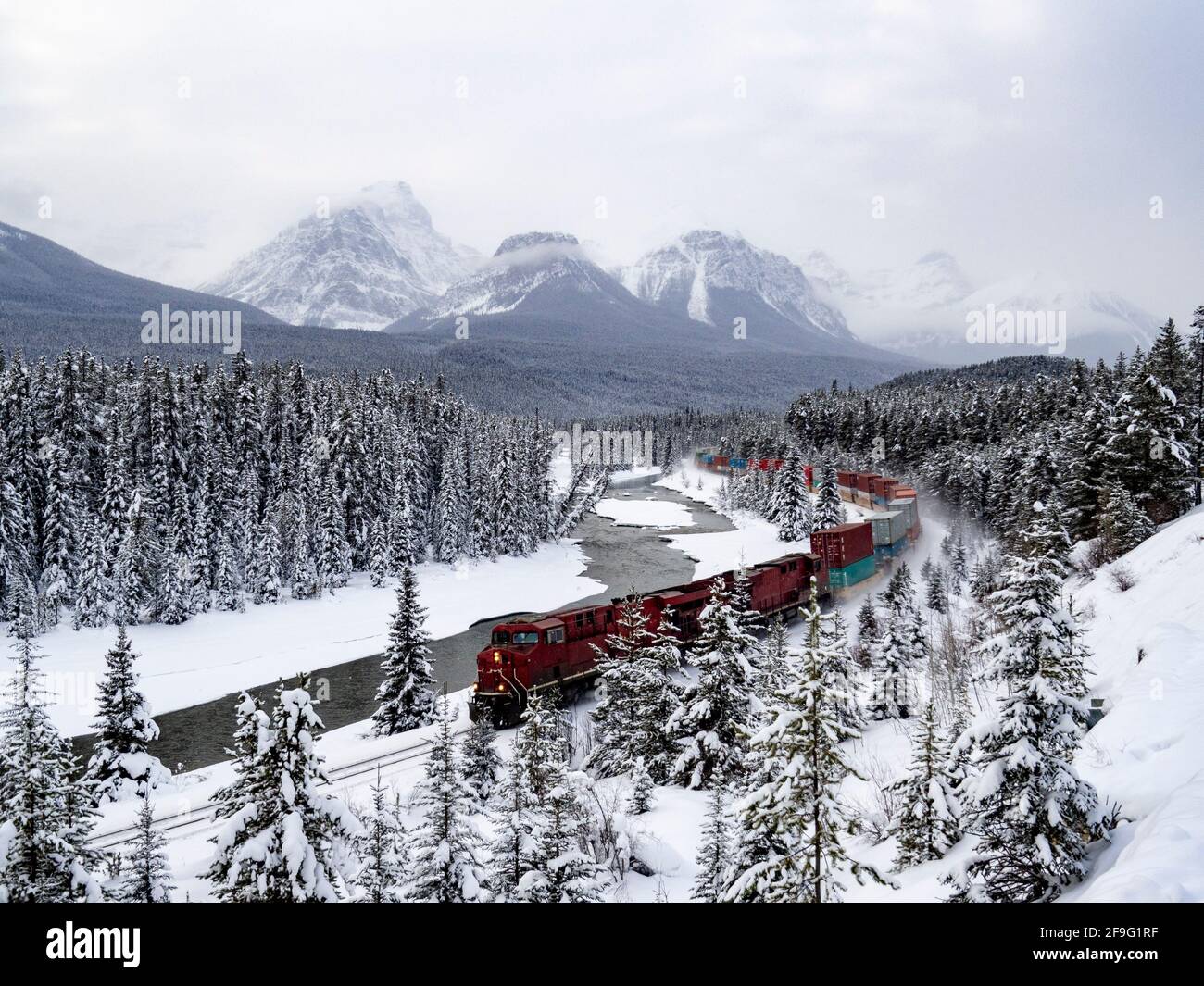 red cargo train in a winter scenery in the mountains with pine trees ...