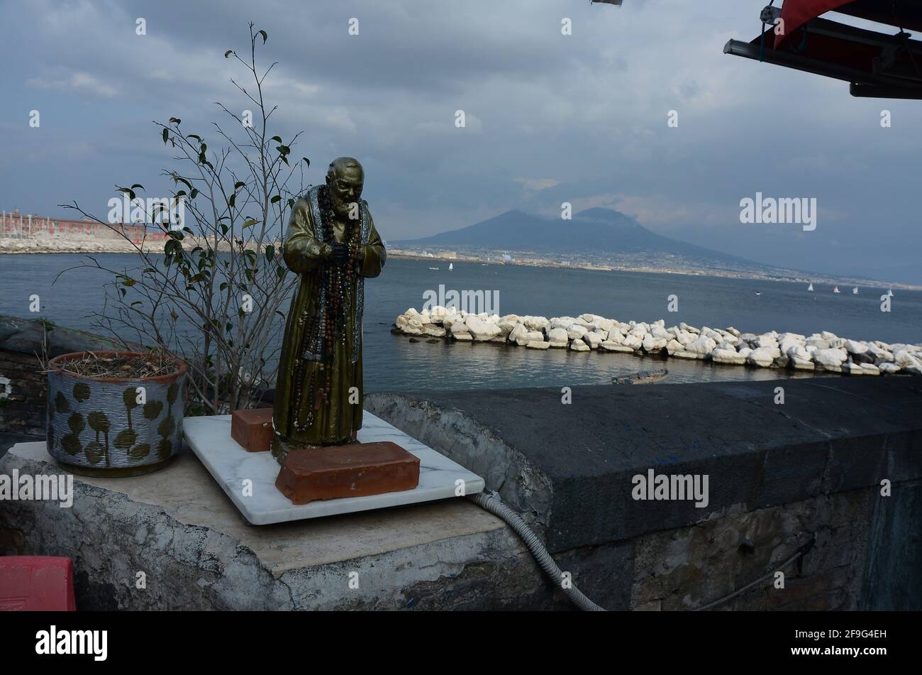 A bronze statue of an old man by the Gulf of Naples and Mount Vesuvius ...