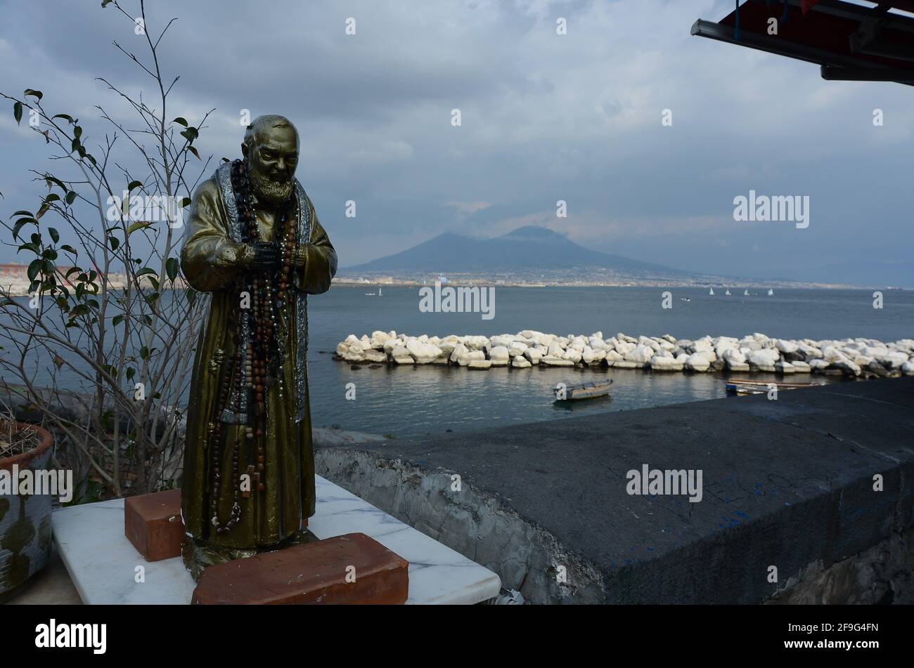 A bronze statue of an old man by the Gulf of Naples and Mount Vesuvius ...