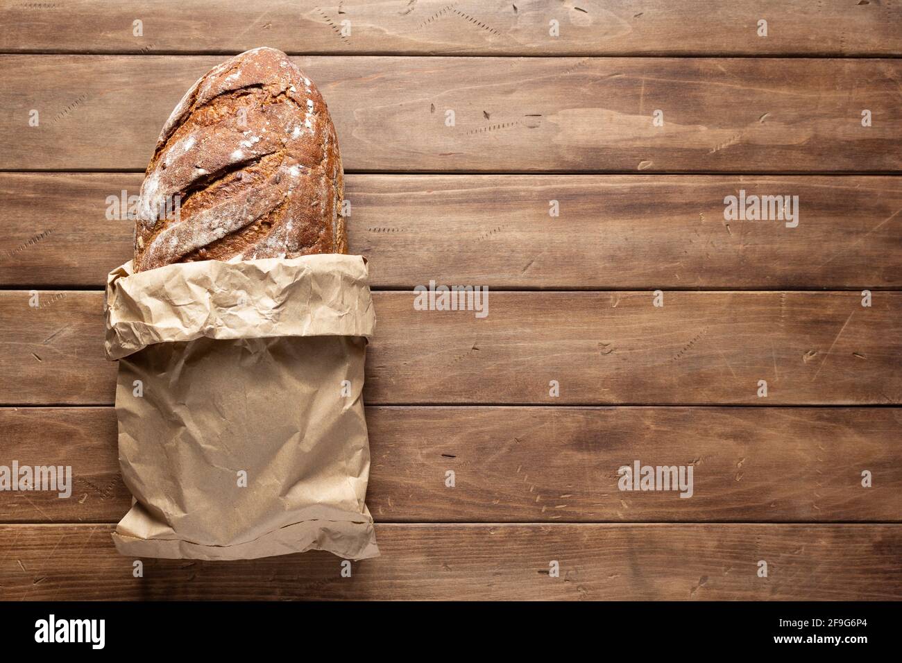 Loaf of fresh bread and buns on wooden table. Bakery food at wood plank ...