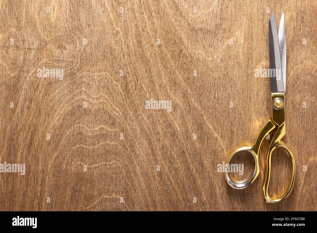 tailor or sewing scissors on wooden table background, flat lay top view ...