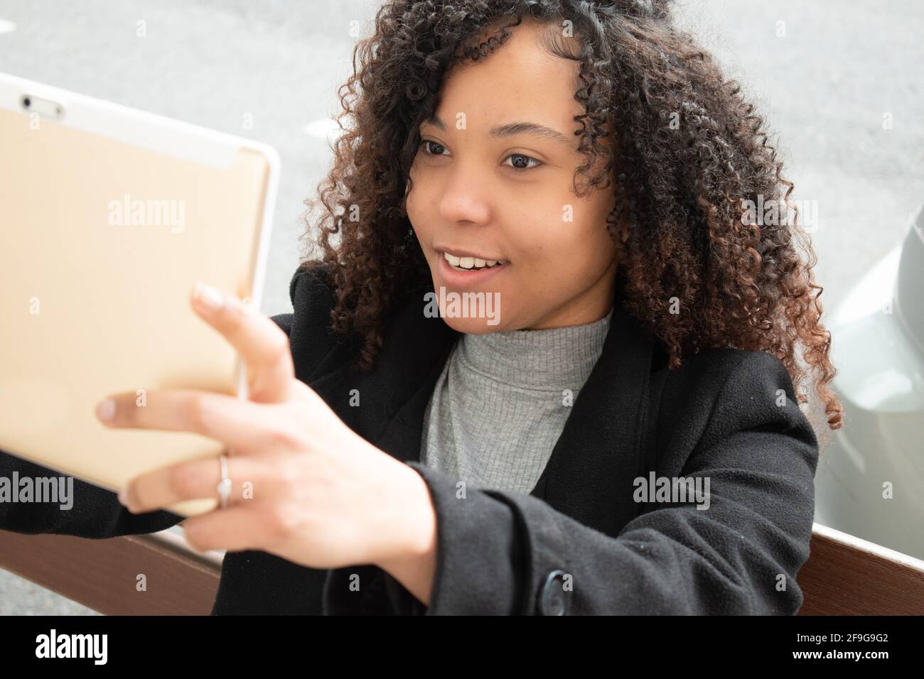 curly-haired woman holds up a tablet while making a video call Stock ...