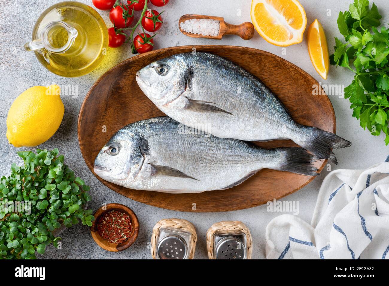 Uncooked dorado fish on wooden tray with a frame of vegetables and ...
