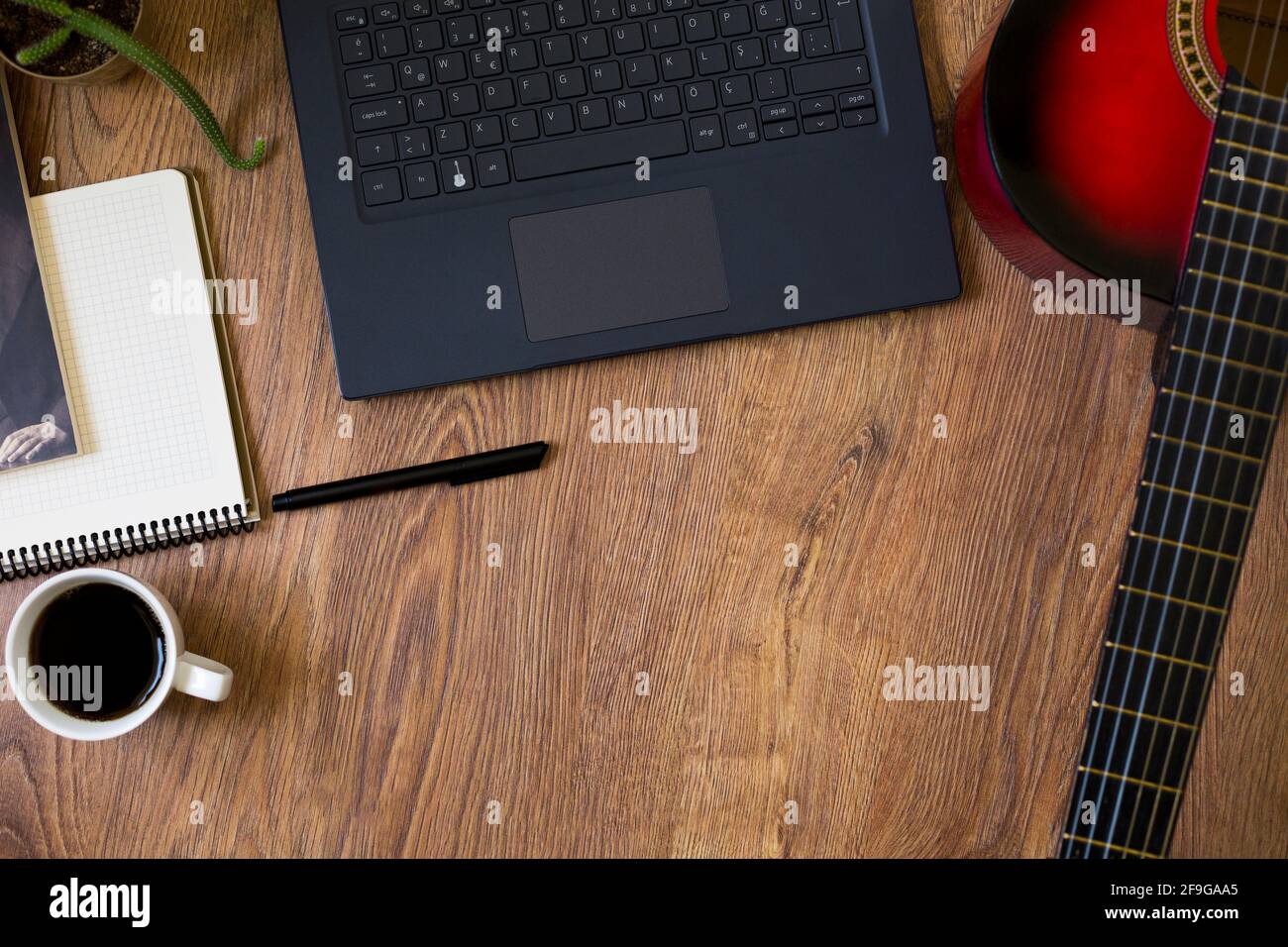 Red-black classical guitar standing on wooden floor, next to computer ...