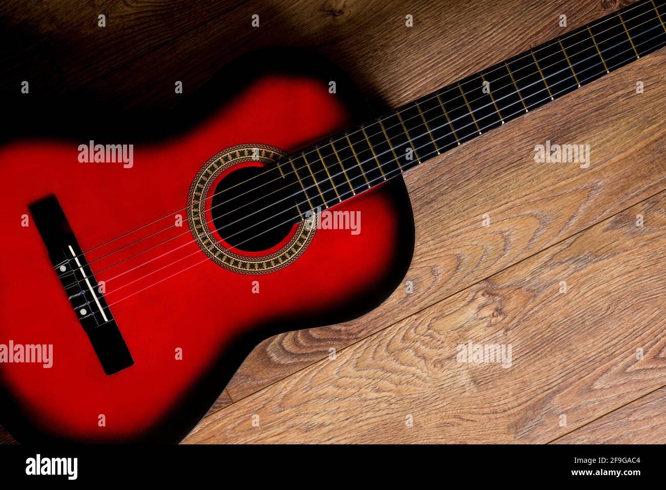 Red-black classical guitar standing on wooden floor Stock Photo - Alamy