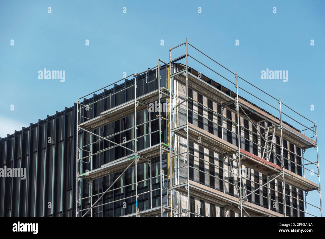 Construction of a modern office building with scaffolding against blue ...