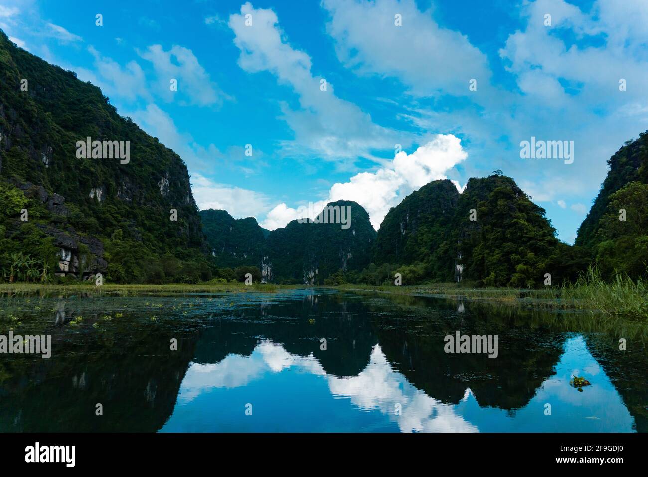 A landscape of a lake surrounded by hills covered in greenery under a ...