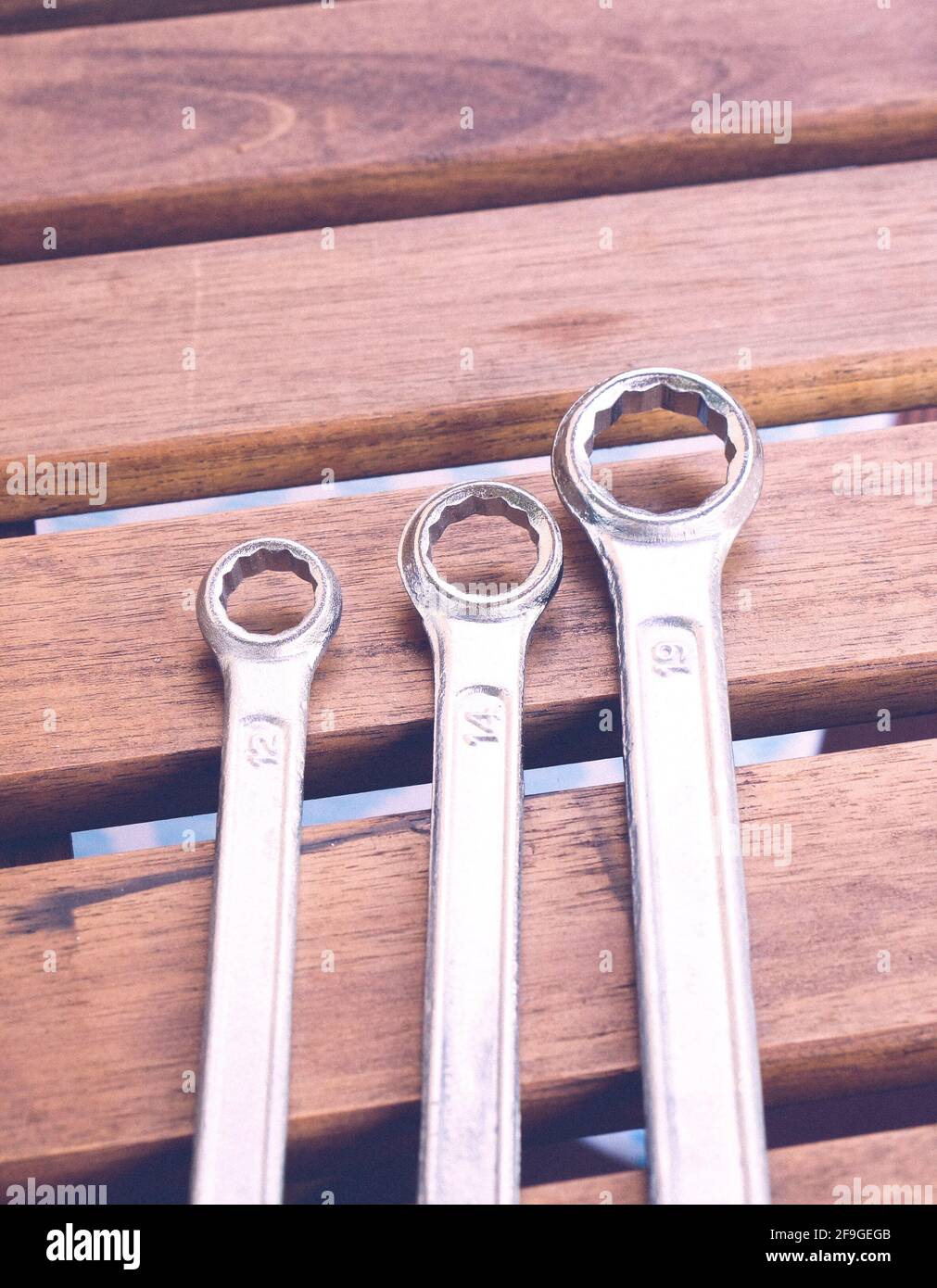 A vertical shot of three different wrenches on a wooden surface Stock ...