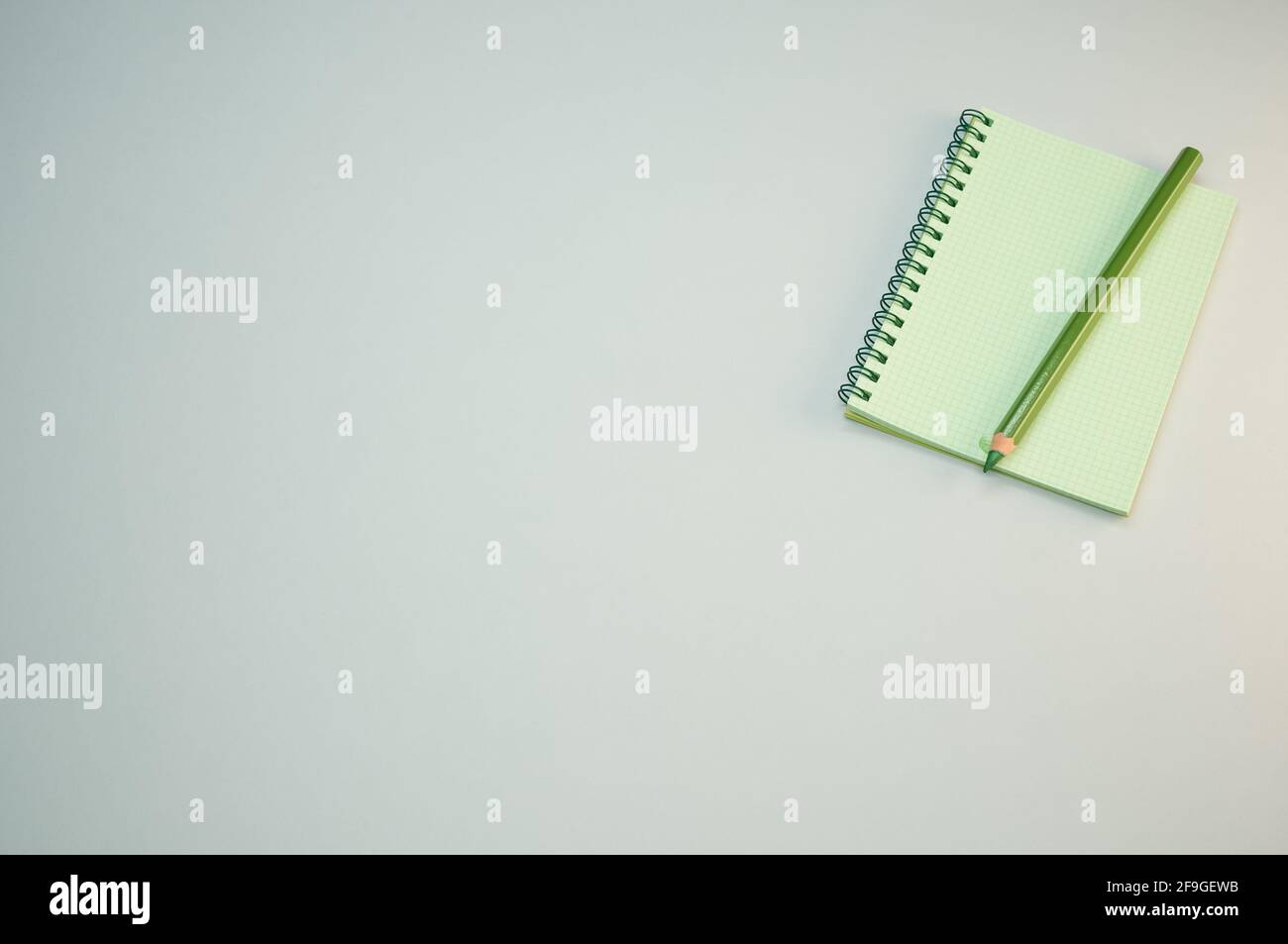 A top view of the green notepad and the green pencil on the gray ...