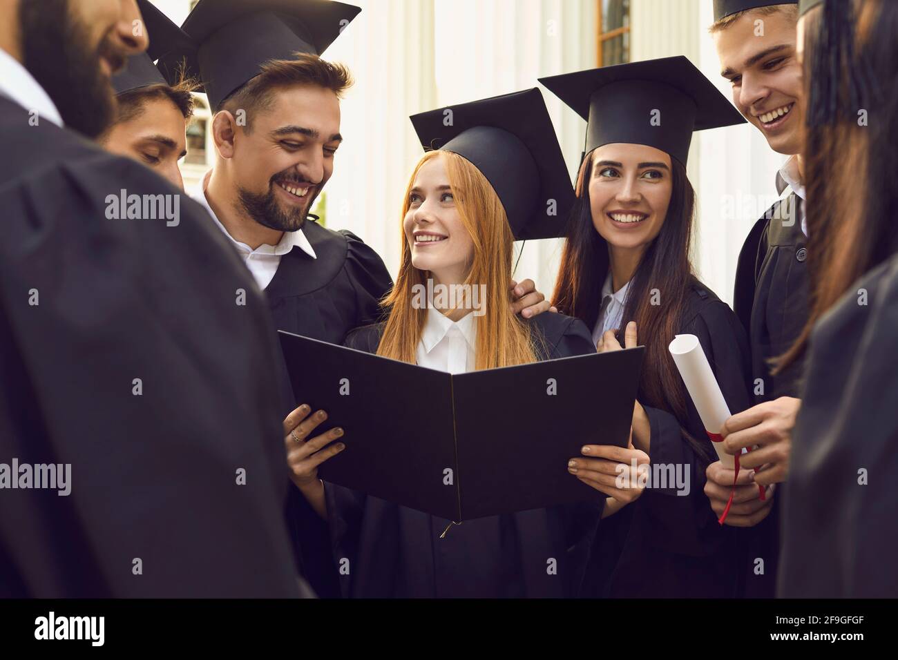 Group of smiling university graduates standing with diplomas and ...