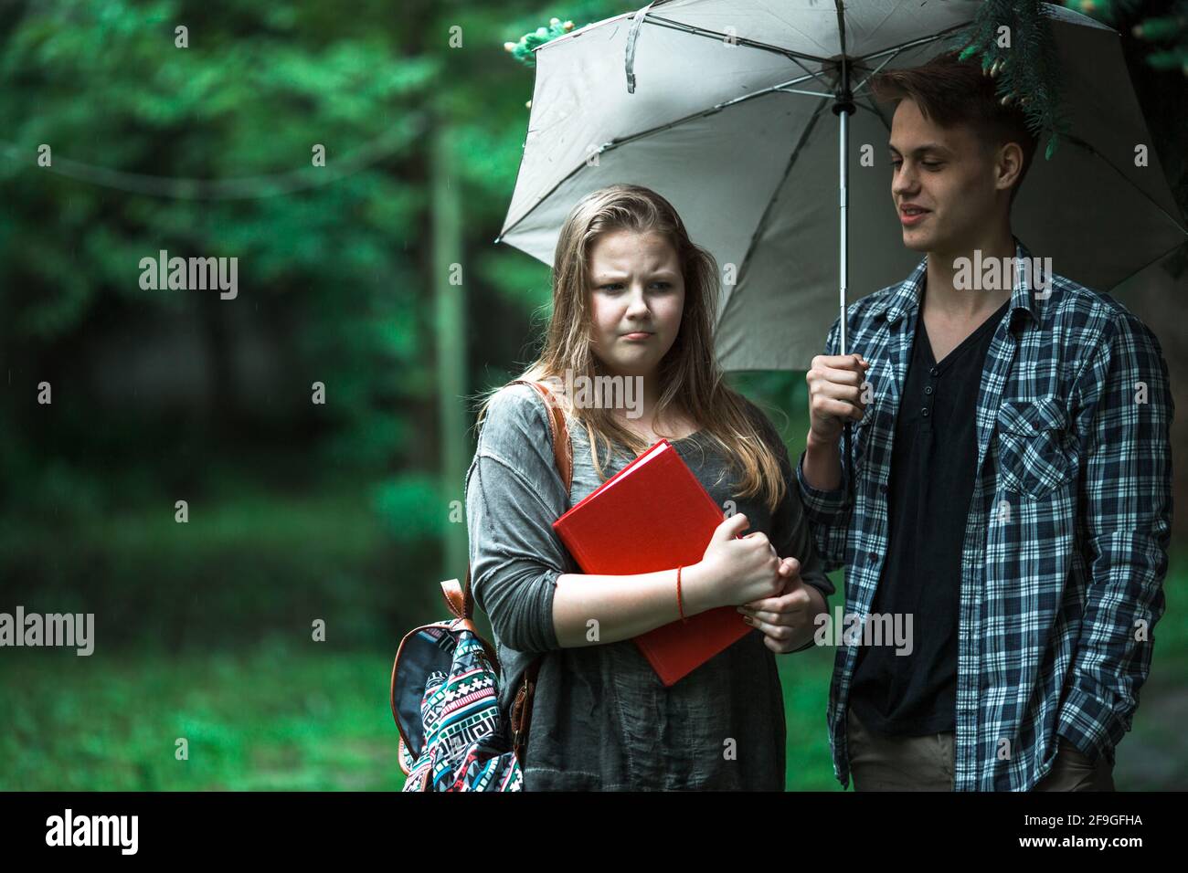 A young couple of outdoors students under an umbrella Stock Photo - Alamy