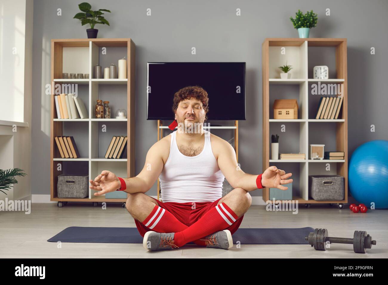 Overweight man with eyes closed sitting on lotus pose and meditating on ...