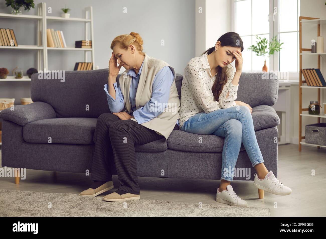 Millennial daughter and older mother sit side by side avoiding ...