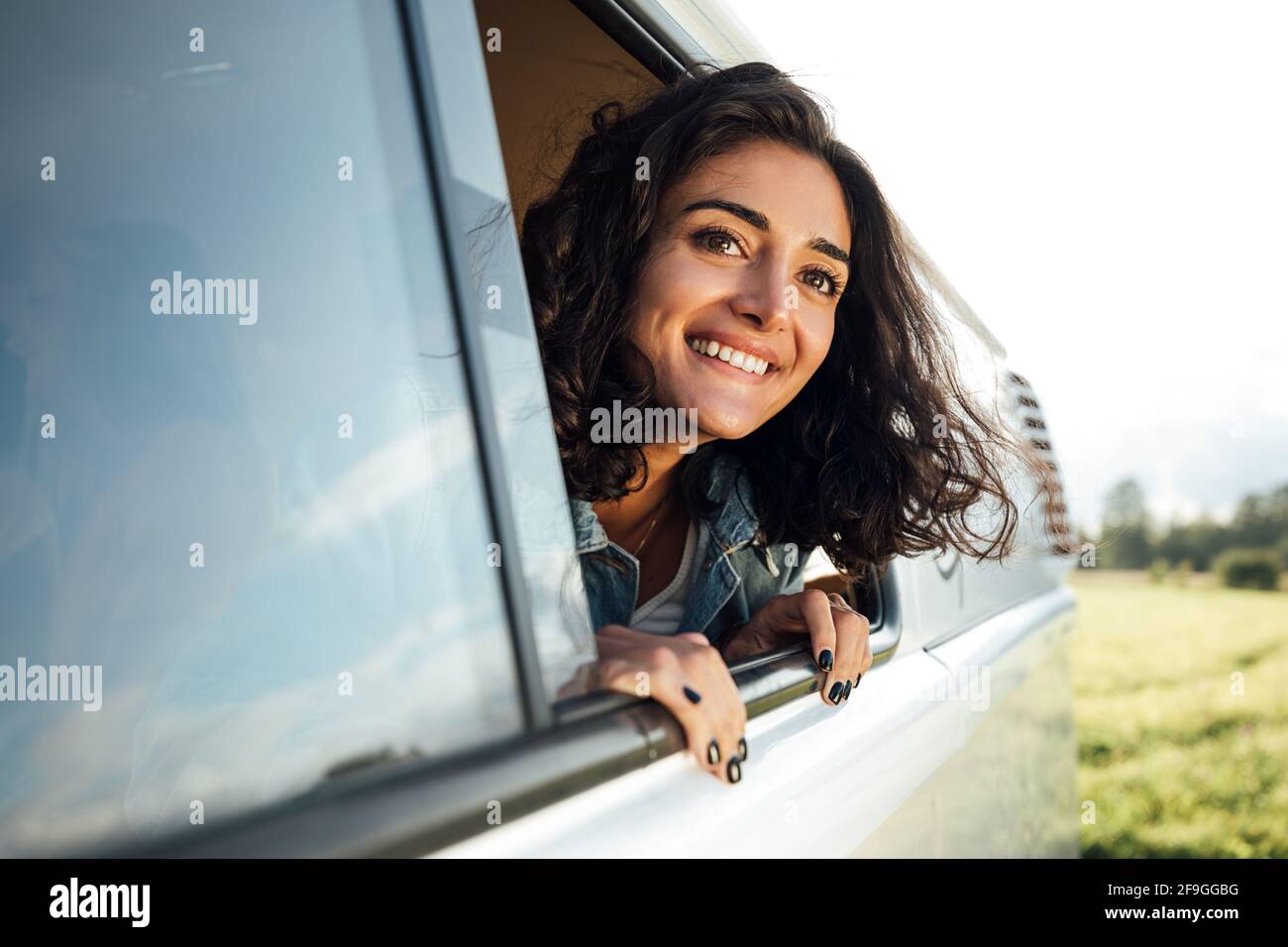 Beautiful brunette looks out of a window enjoying a road trip. Young ...