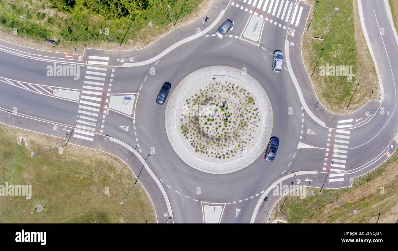 An overhead shot of cars in the roundabout with greenery on the sides ...