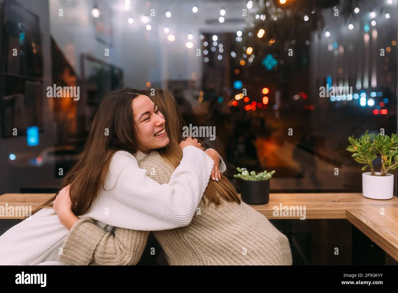 Portrait of happy cute young friends hugging each other at caffe Stock ...