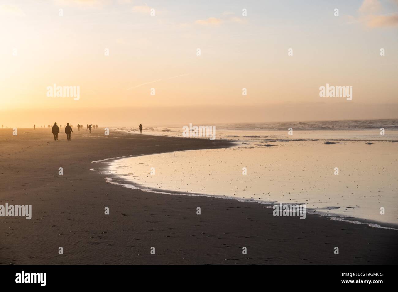 People walking in the haze at sunset on the beach, Langeoog, East ...