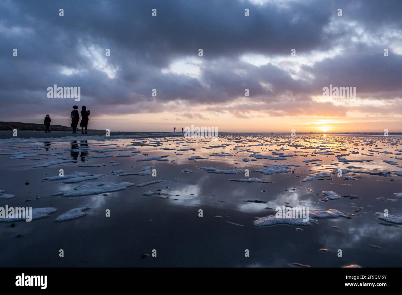Couple taking photos at sunset on the beach, Langeoog, East Frisian ...