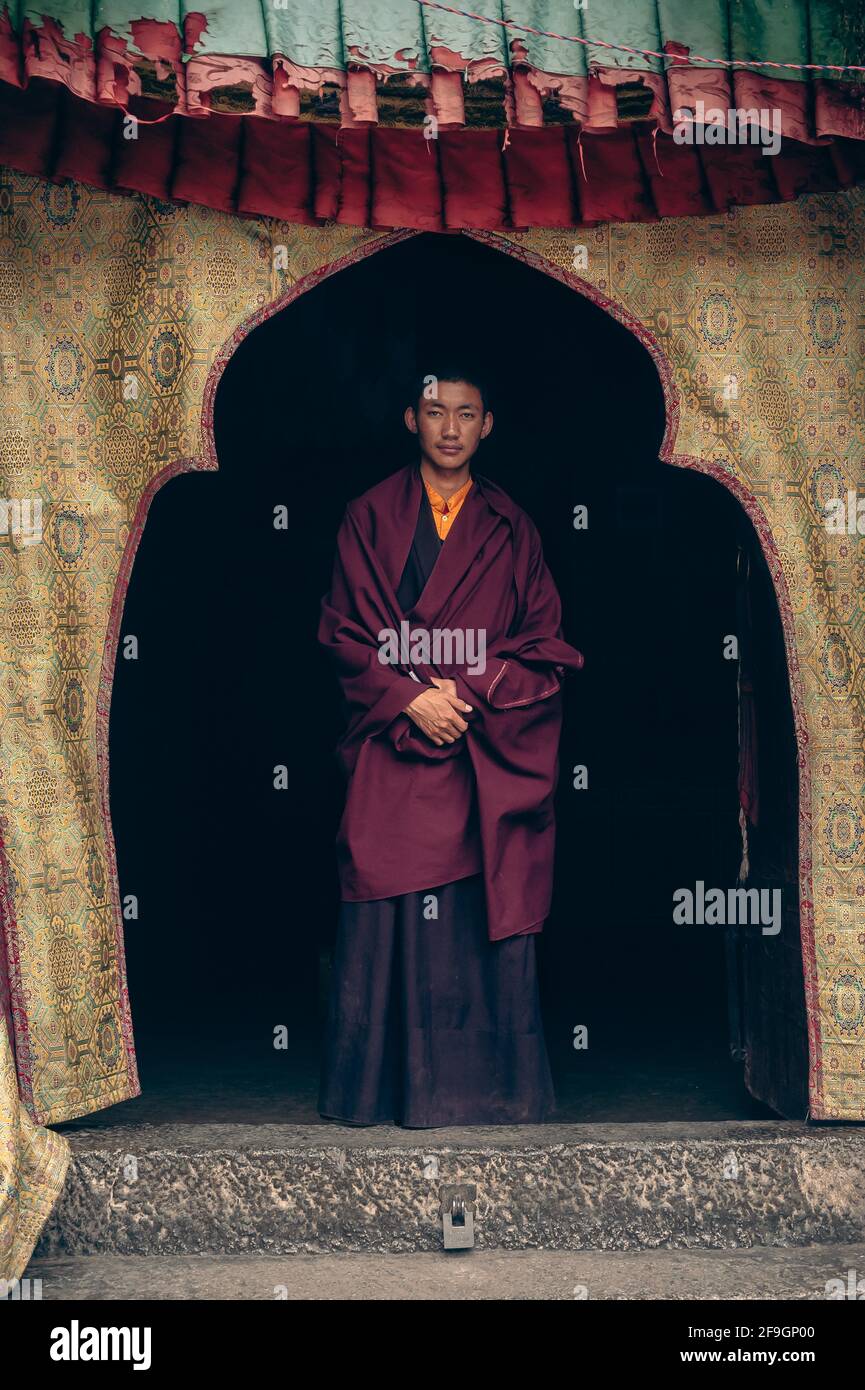 A young monk in red garb stands in the entrance to Samye monastery ...