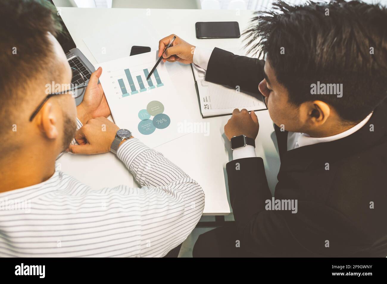 Young office worker sitting at desk, using computer. Two business man ...