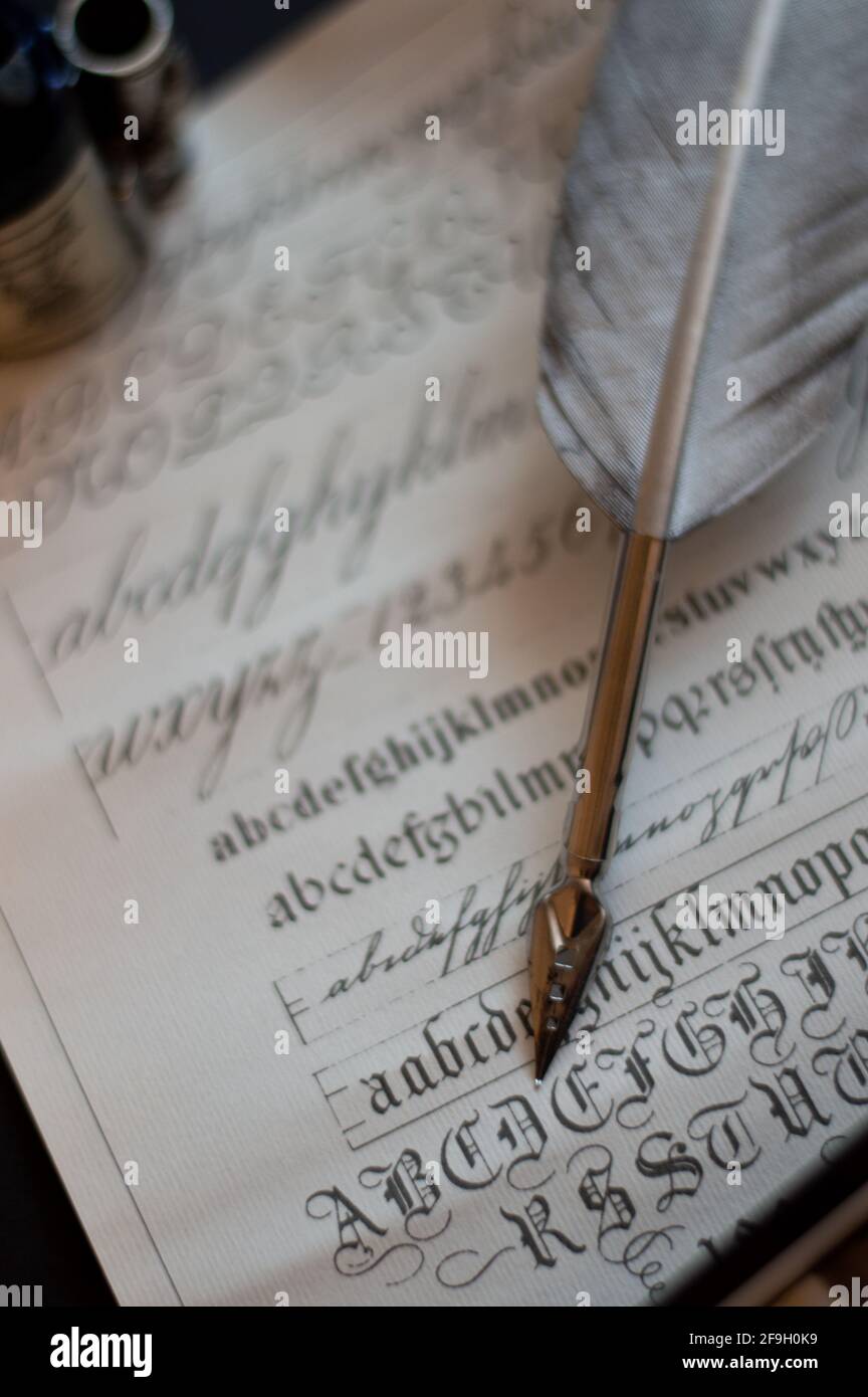 A vertical shot of a quill set and an ink bottle on a piece of paper ...