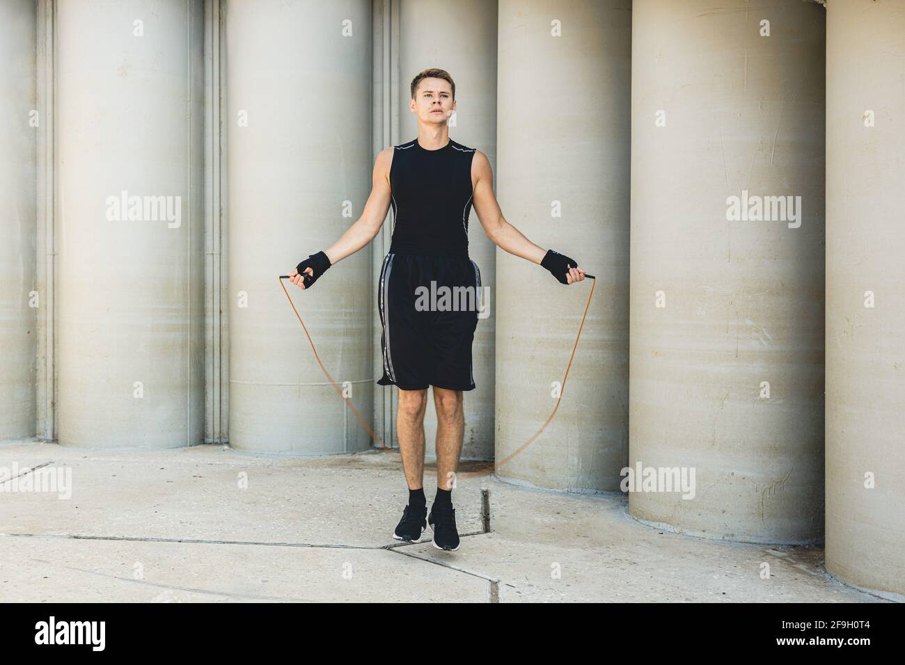 Caucasian man fighter training hard in the outdoors.. Man using rope ...